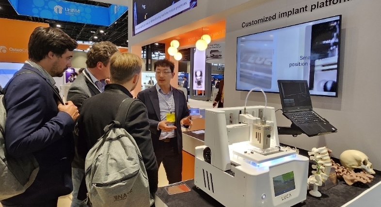 [사진2] NASS 2022에 설치된 시지바이오 부스에서 제품 담당자가 PSI 시스템에 대해 소개하고 있다. – CGBIO